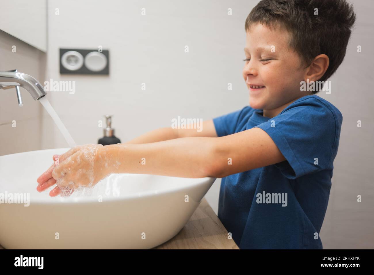 Side view kid washing hands at sink with pouring soapy and tap water ...