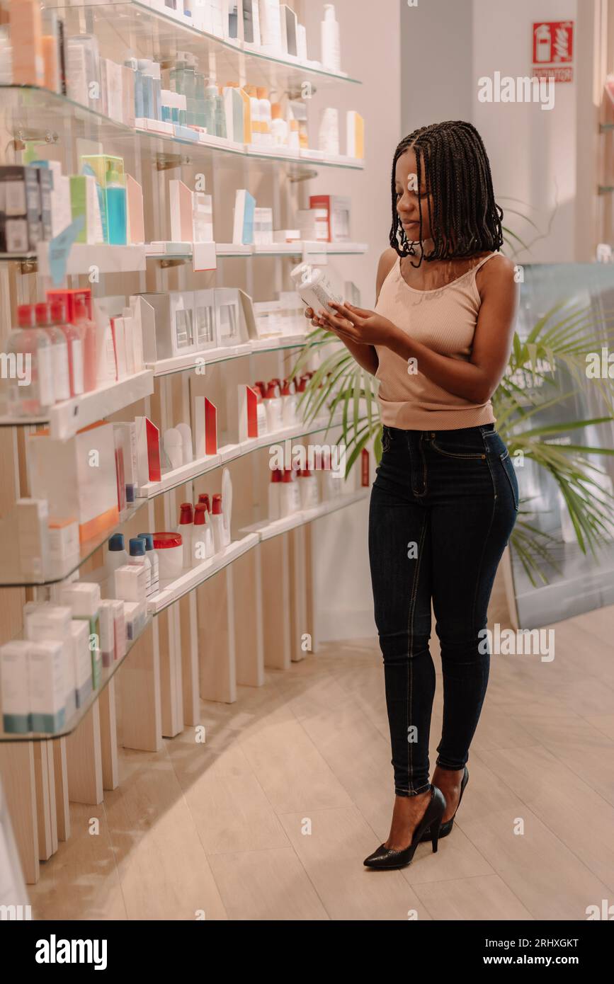 Side view of African American young woman with dreadlocks reading ...