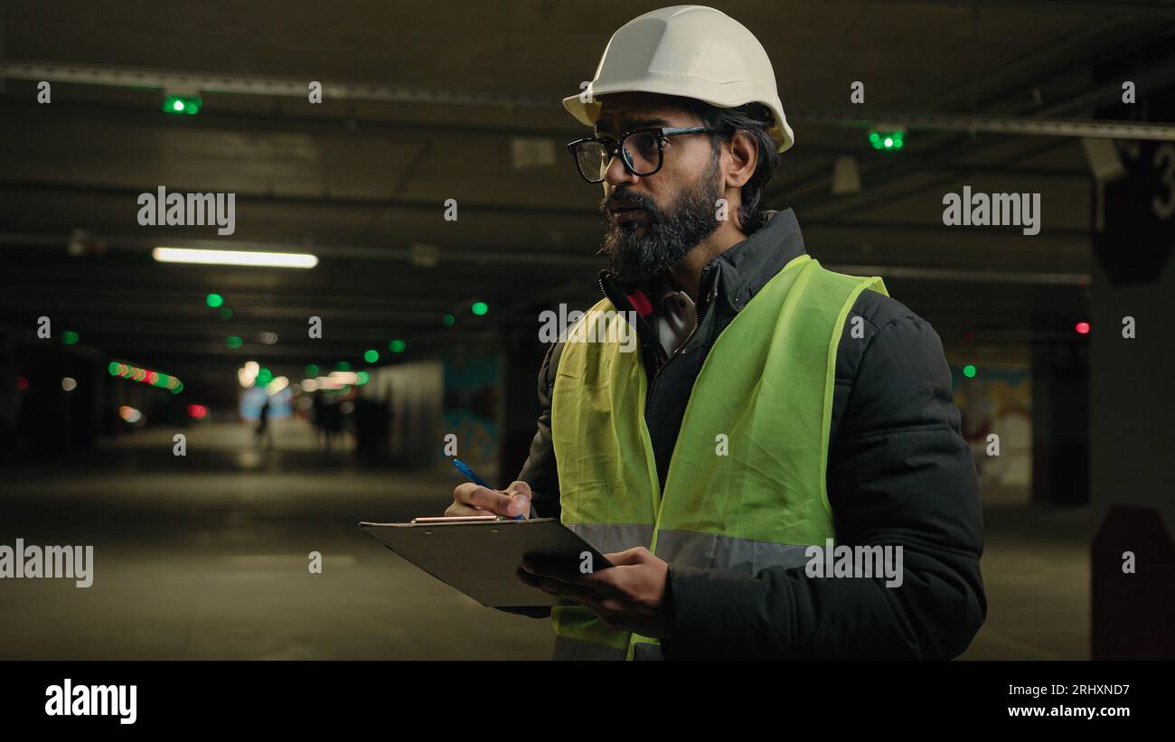Indian contractor mechanic in helmet and glasses writing in paper ...