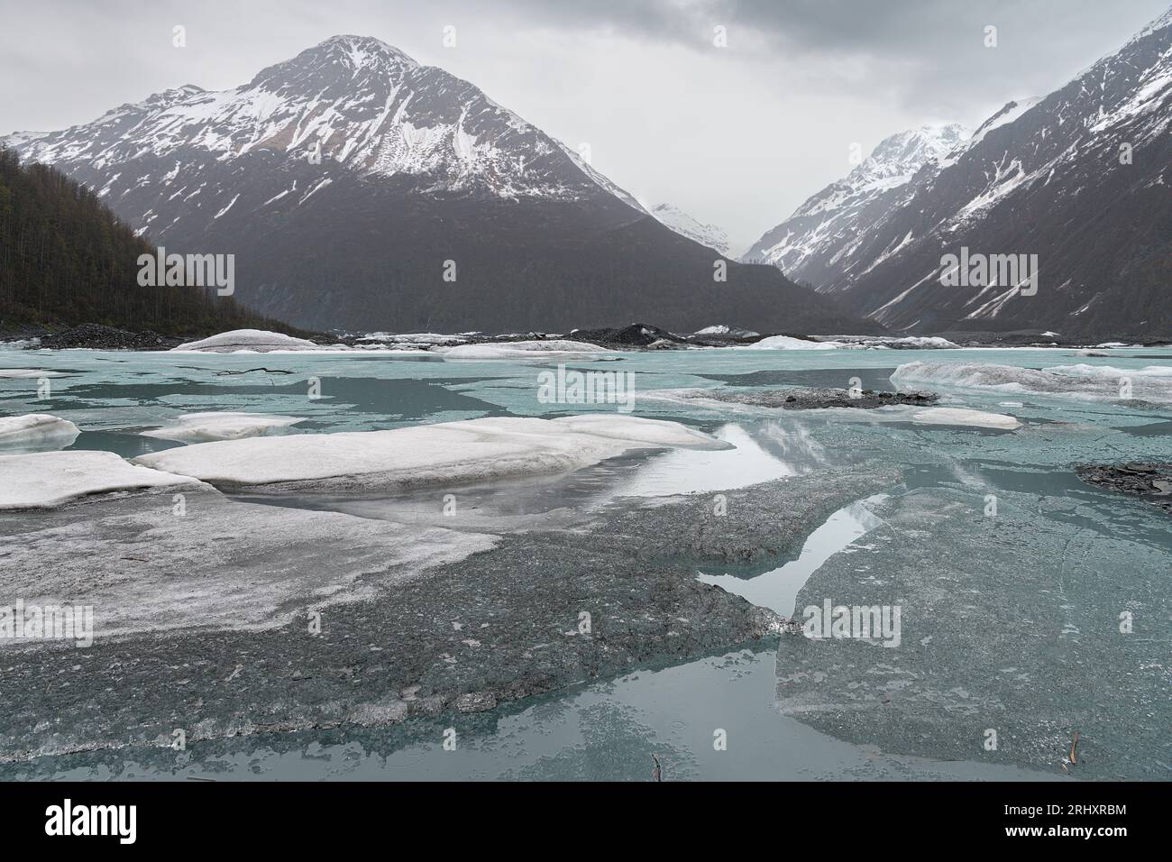 Ice sheets on Valdez Glacier Lake with distance mountains in rain and ...