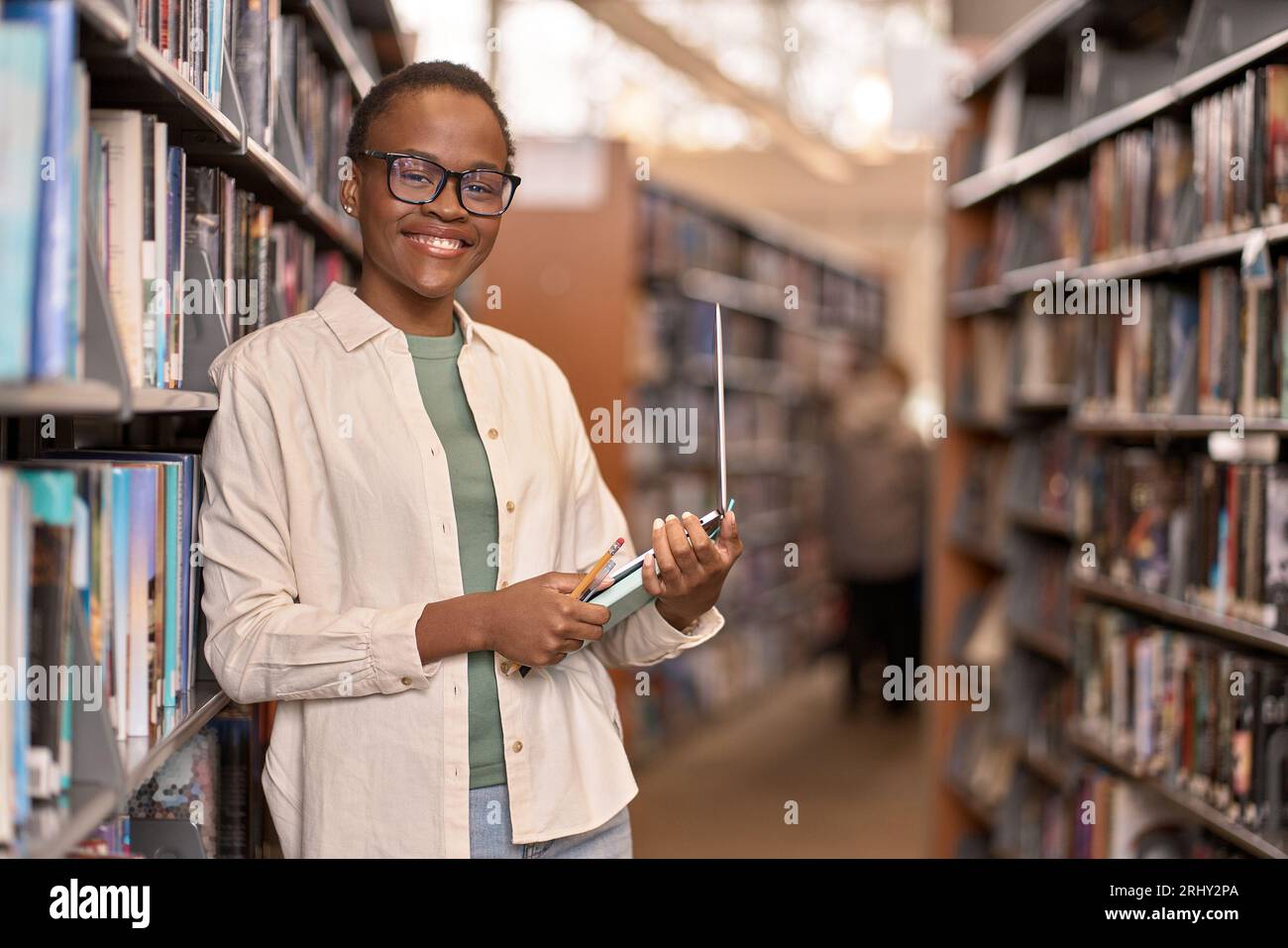 Happy African girl student holding laptop standing in library. Portrait ...