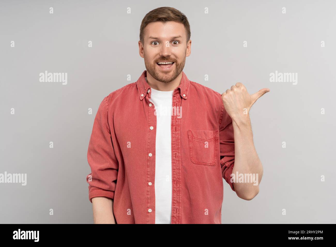 Man points with his thumb to side. Portrait of glad cheerful man ...