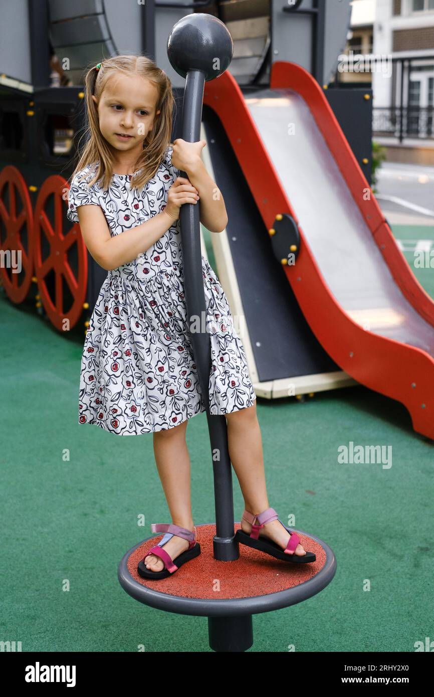 Child playing on playground in the city. Girl spinning and balancing ...