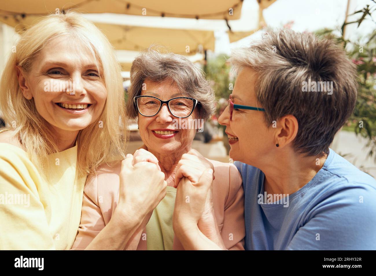 Happy middle age women are hugging and look at camera while sitting in ...