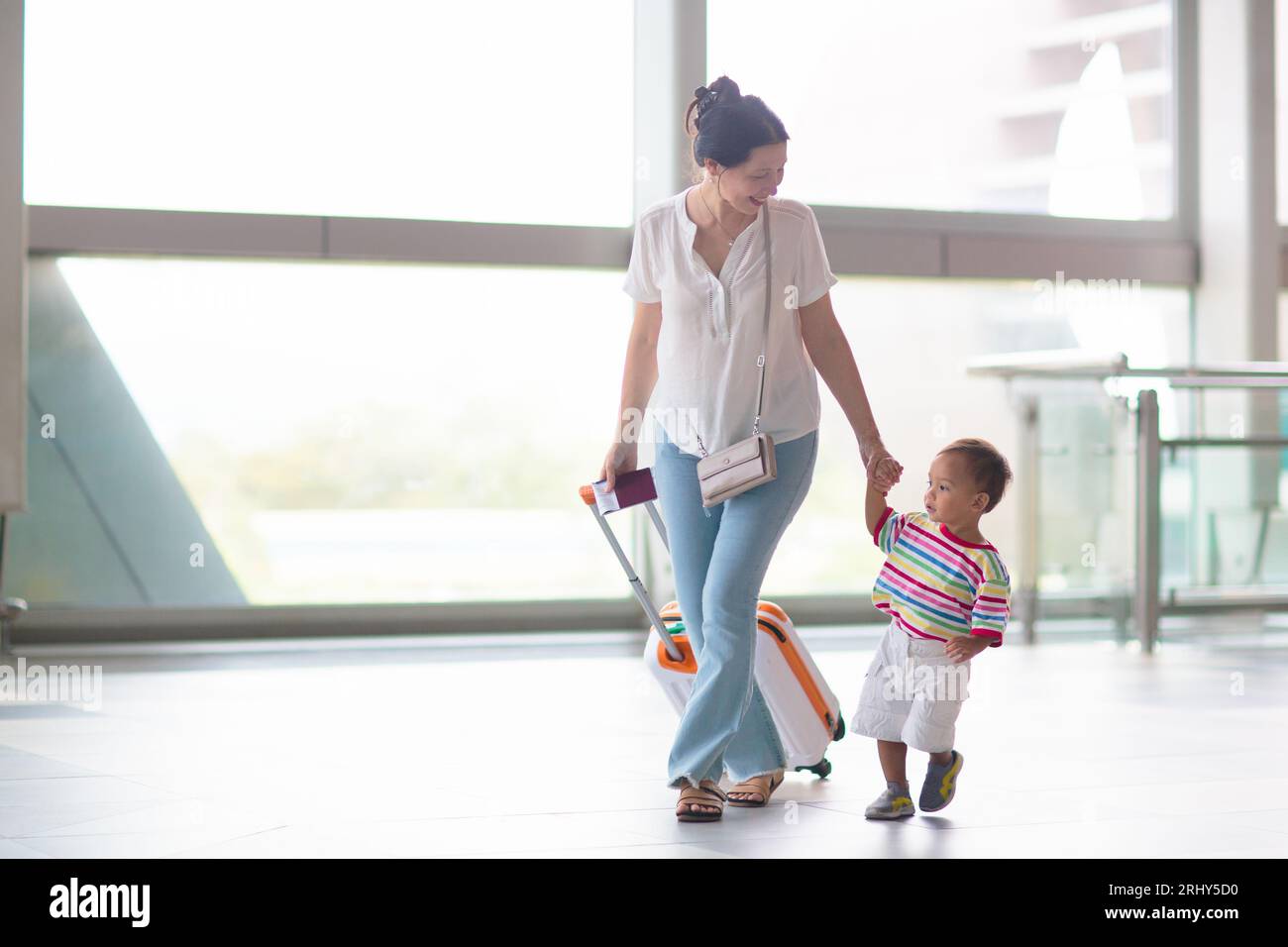 Family in airport. Young Asian mother and child travel by air. Fly with ...