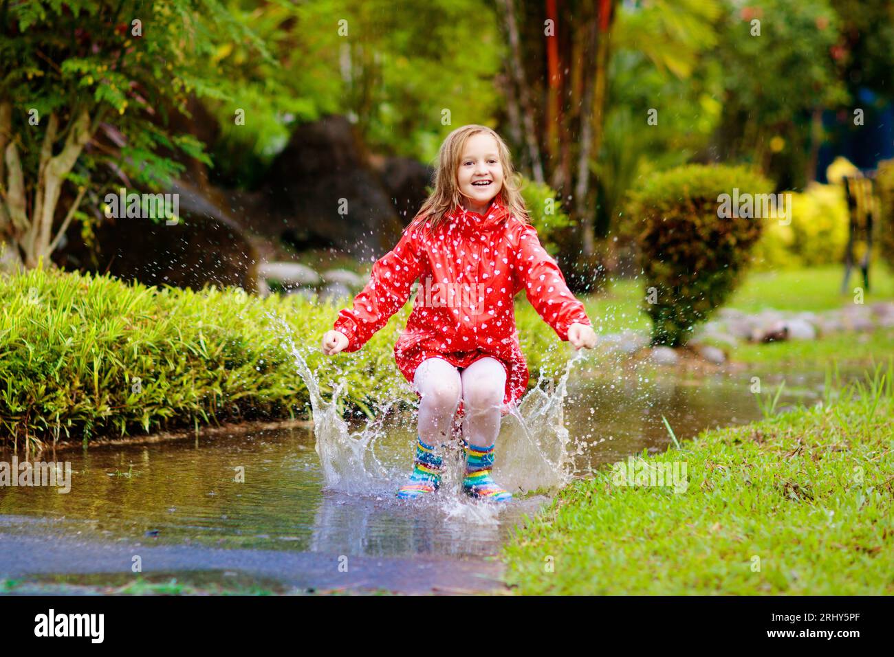 Child playing in puddle. Kids play and jump outdoor by autumn rain ...