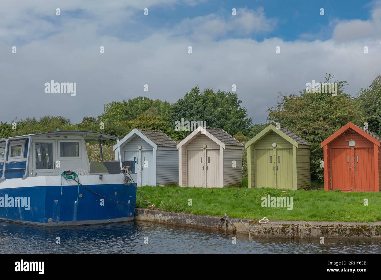 Blue boat moored on a canal next to some different coloured huts Stock ...