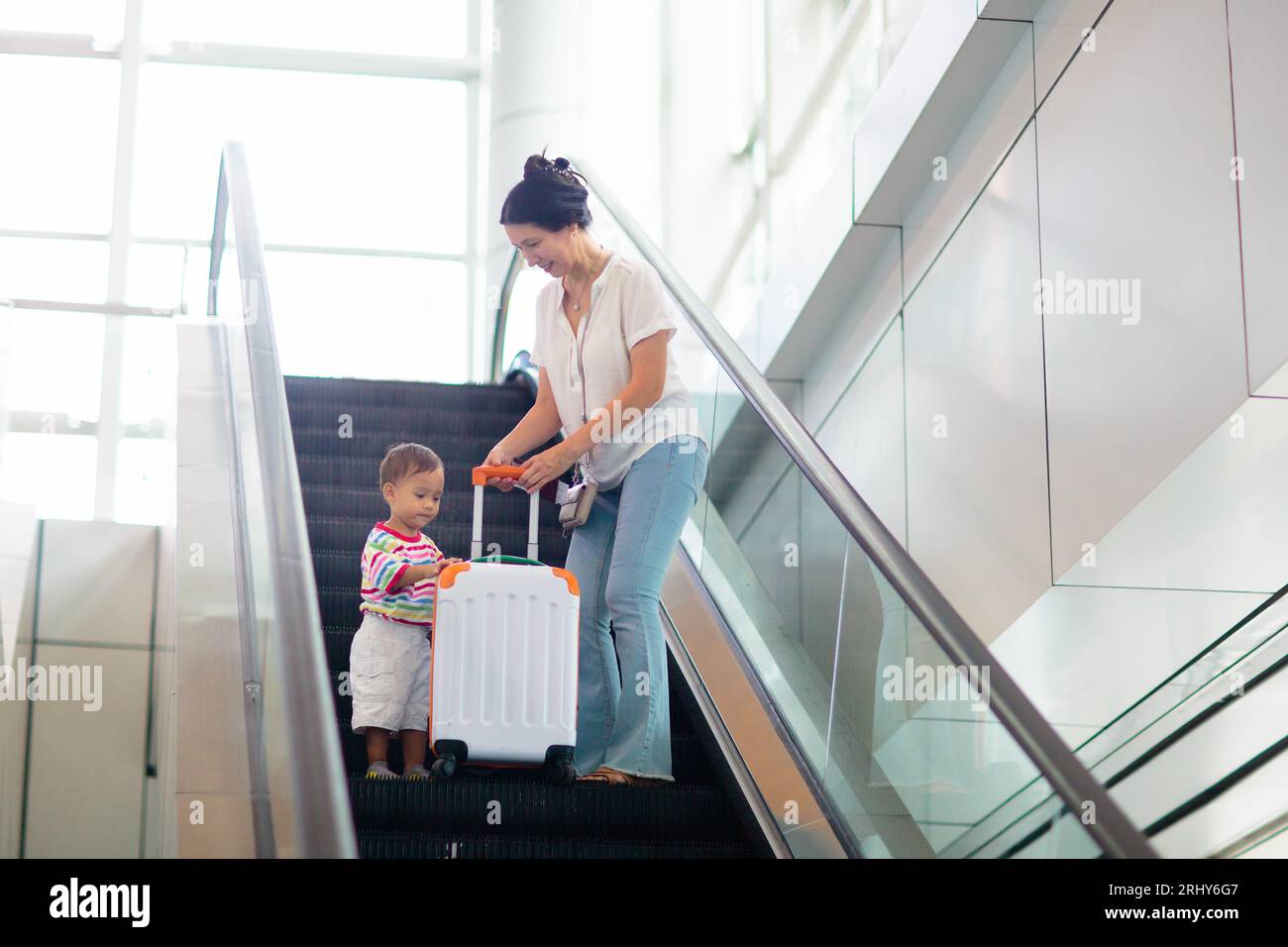 Family in airport. Young Asian mother and child travel by air. Fly with ...