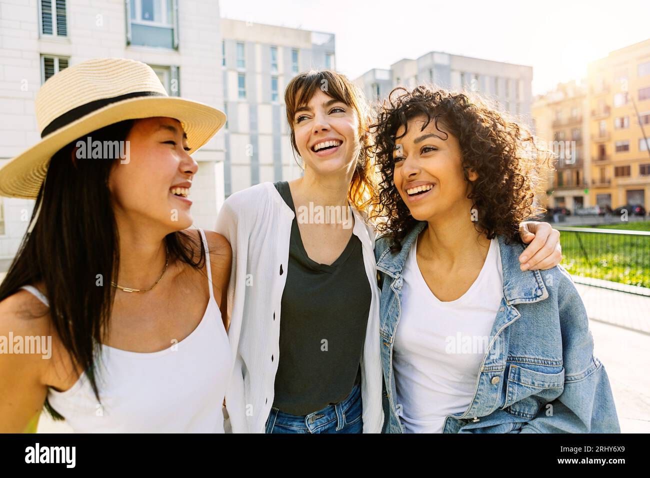Three happy young female friends hanging out together in city street ...