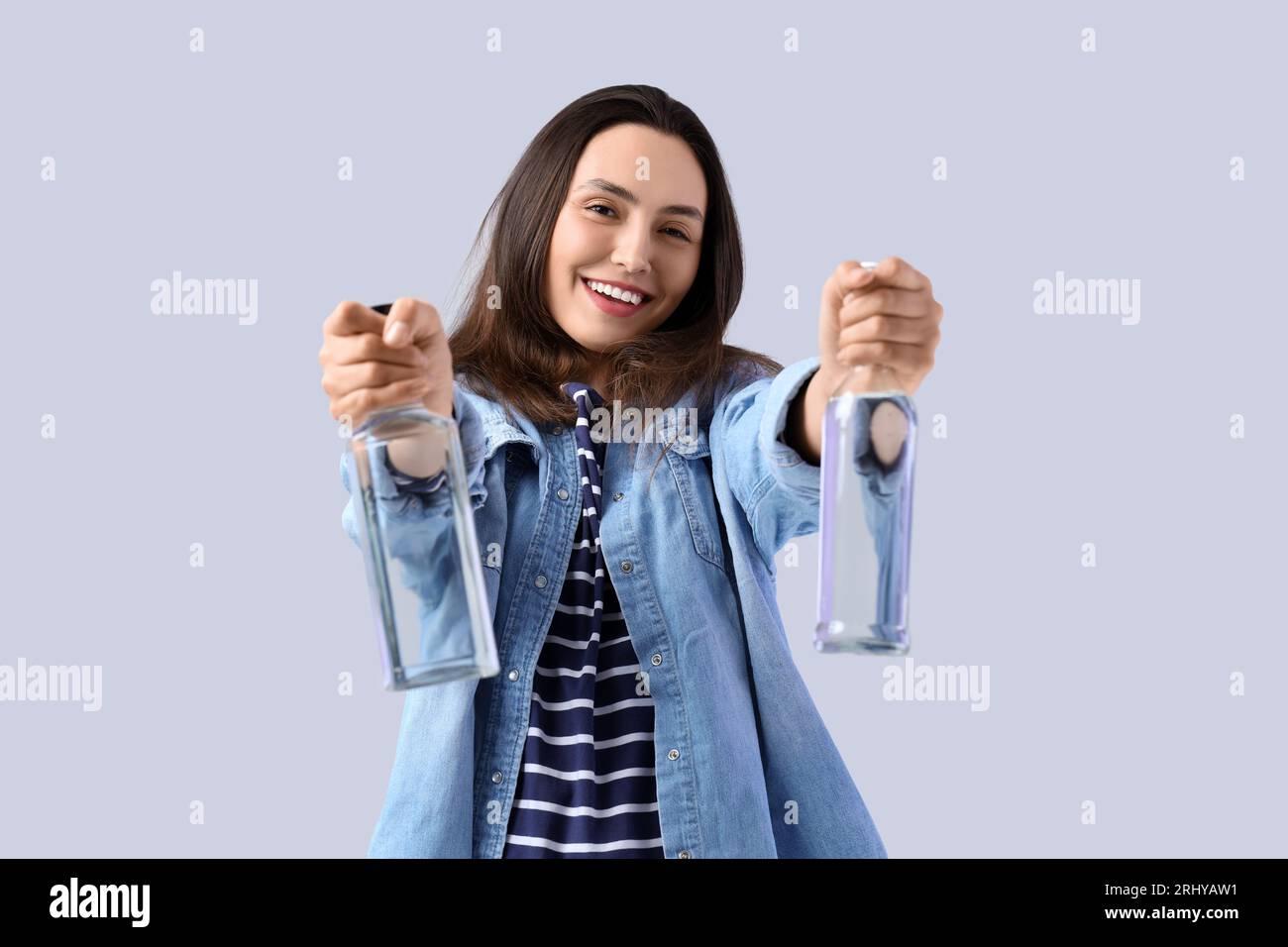 Drunk young woman with bottles of vodka on light background Stock Photo ...