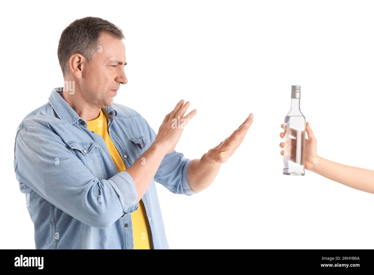 Displeased mature man rejecting bottle of vodka on white background ...