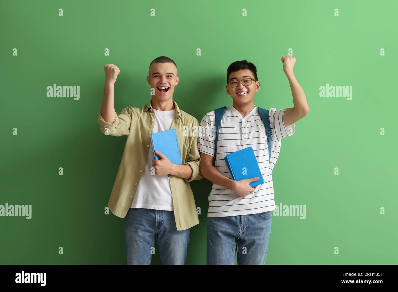 Happy male students with books on green background Stock Photo - Alamy