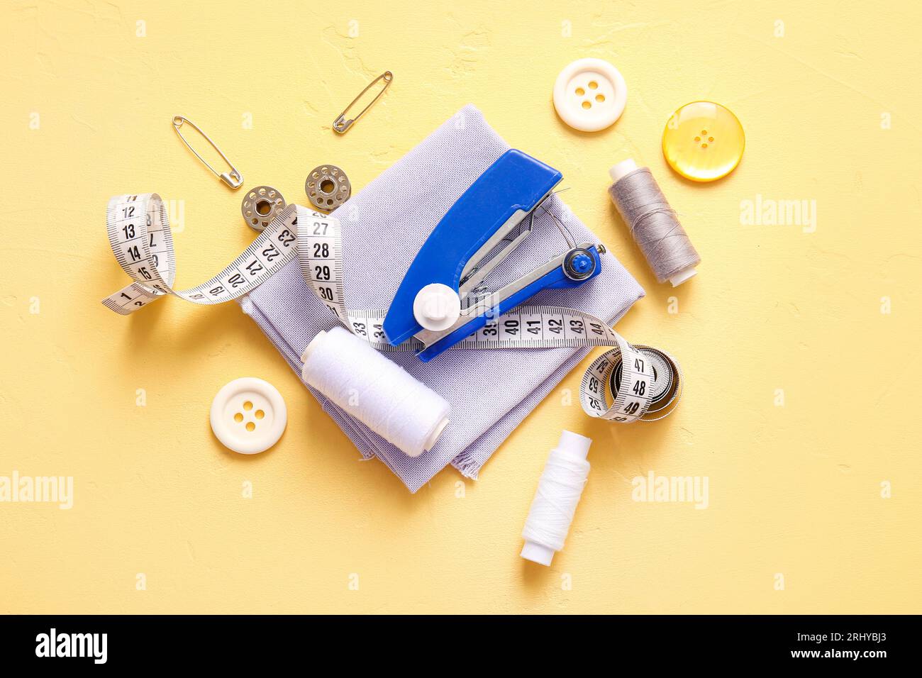 Manual sewing machine with different supplies on yellow background ...