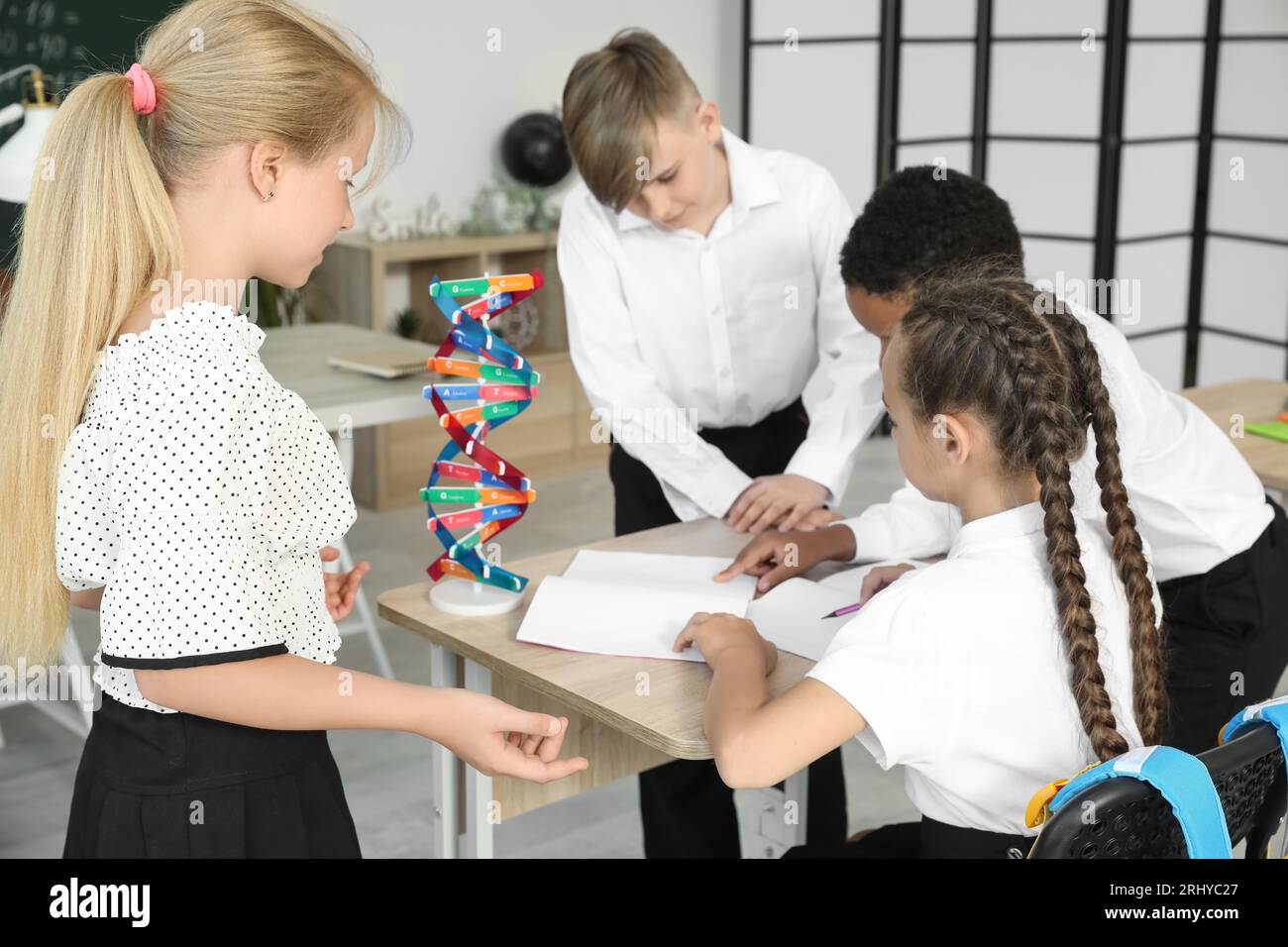 Little classmates writing at desk in classroom Stock Photo - Alamy