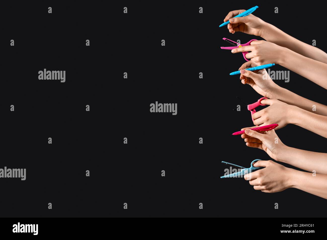 Many female hands with different pens and scissors on black background ...
