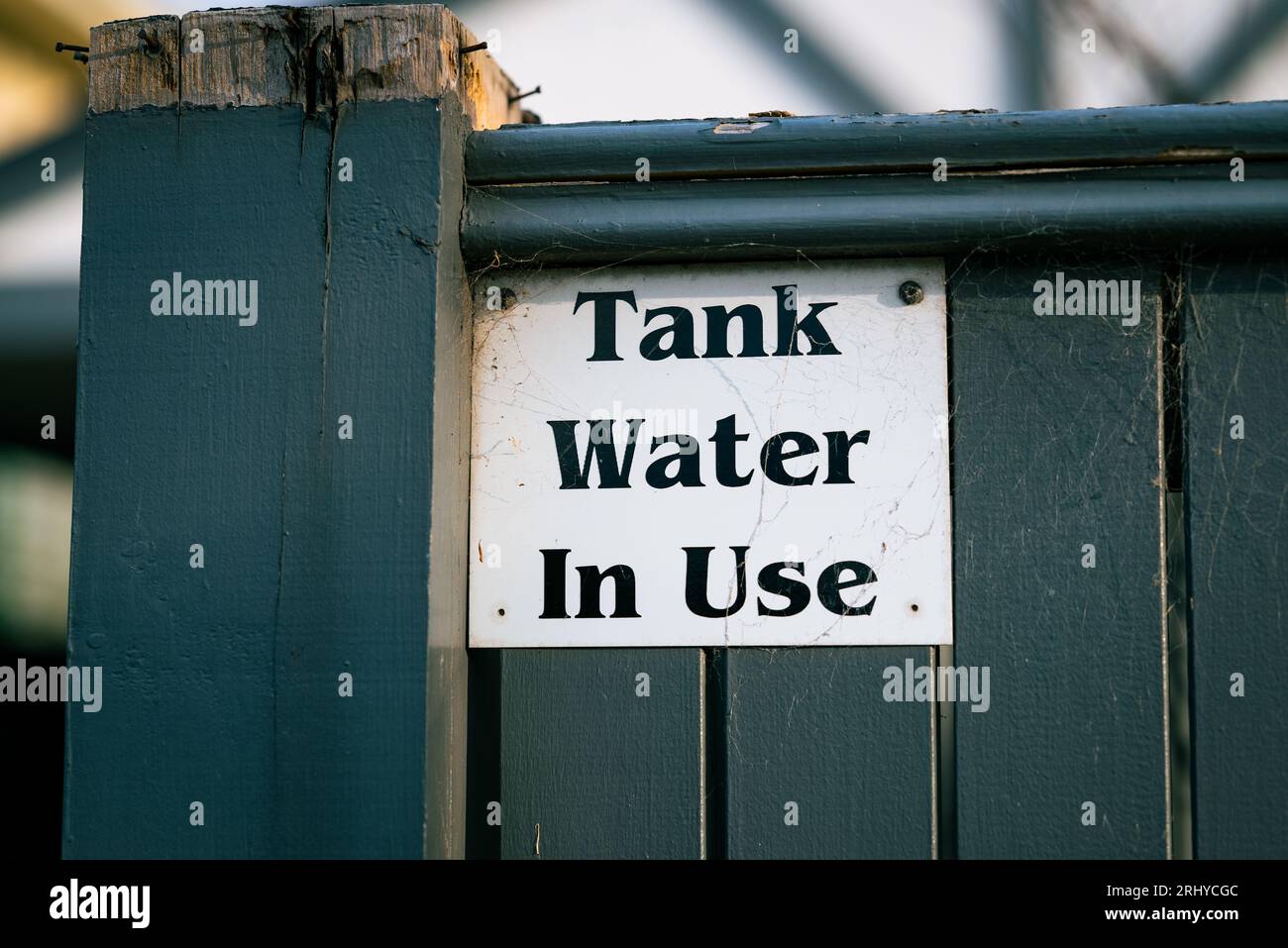 Cobweb covered white tank water in use sign, featuring black text, on a ...