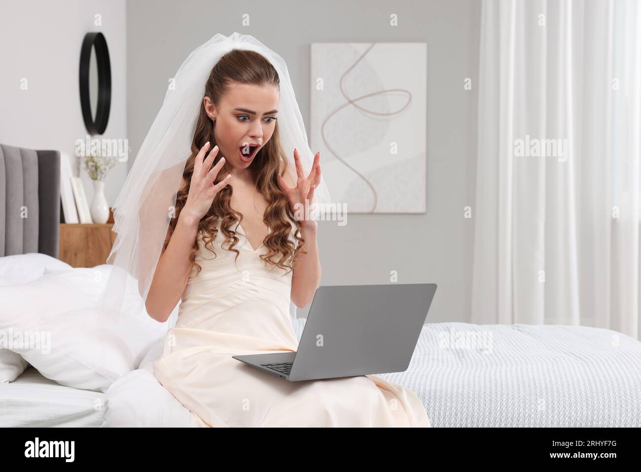 Shocked bride with laptop on bed in bedroom Stock Photo - Alamy