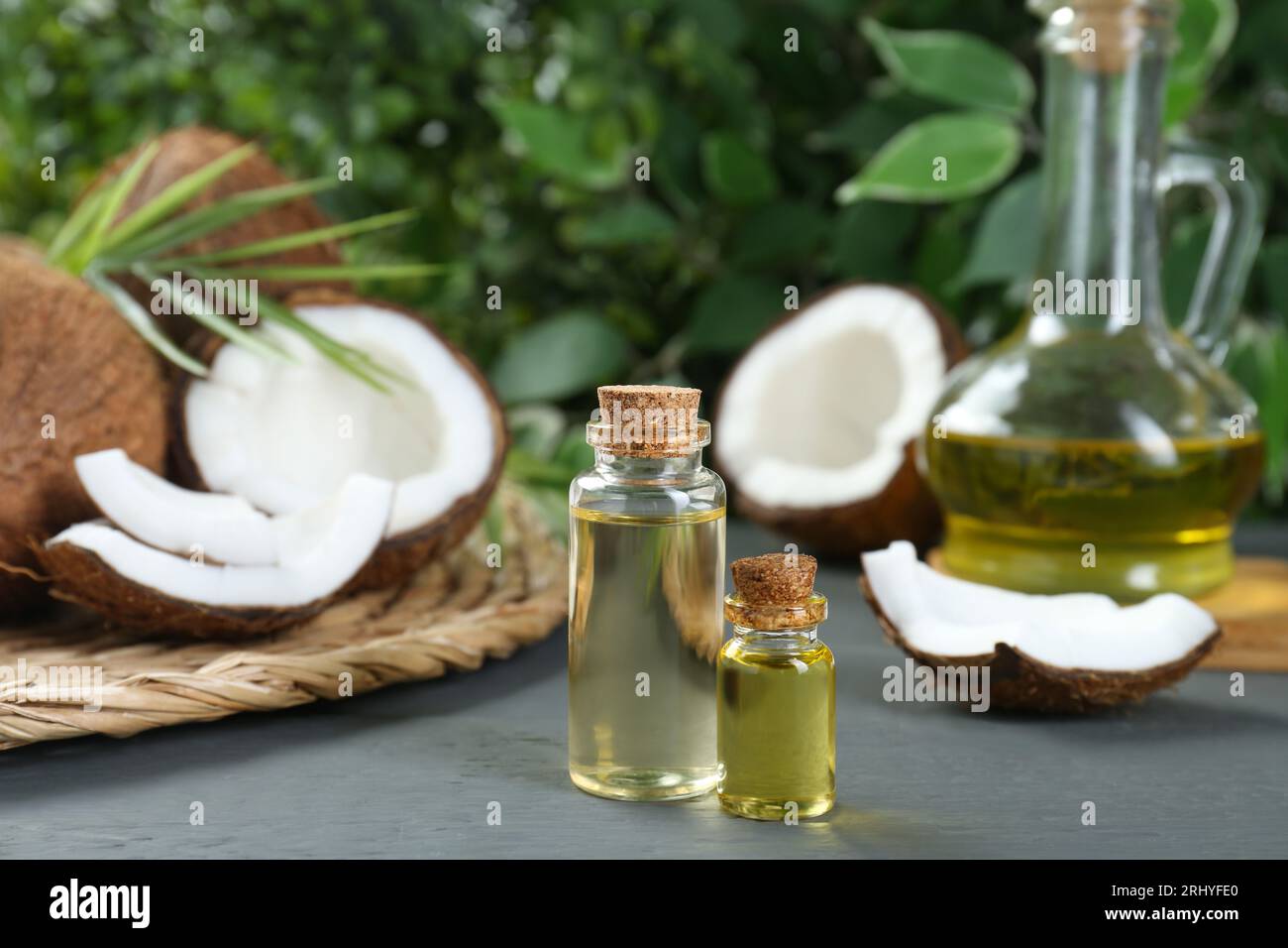 Bottles of organic coconut cooking oil and fresh fruits on grey table ...