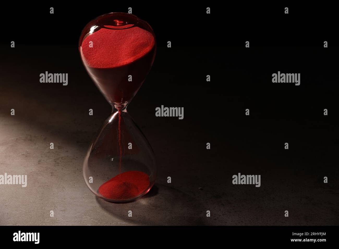 Hourglass with red flowing sand on grey table. Space for text Stock ...