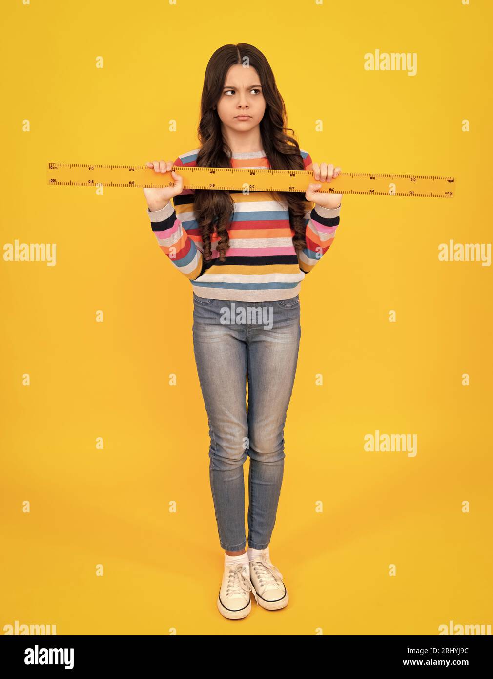Back to school. School girl hold ruler measuring isolated on yellow ...