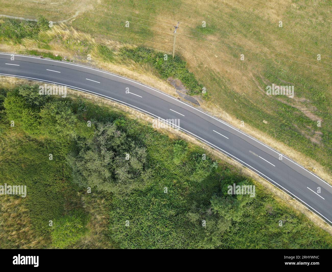 Aerial view of a road between trees and grass fields in the landscape ...
