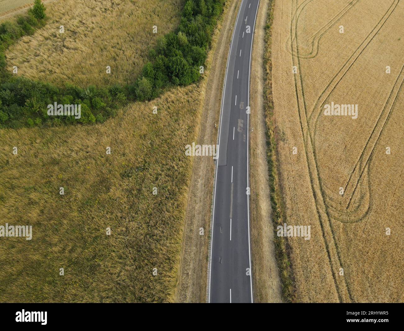 Aerial view of a road between crop and grass fields in the landscape ...