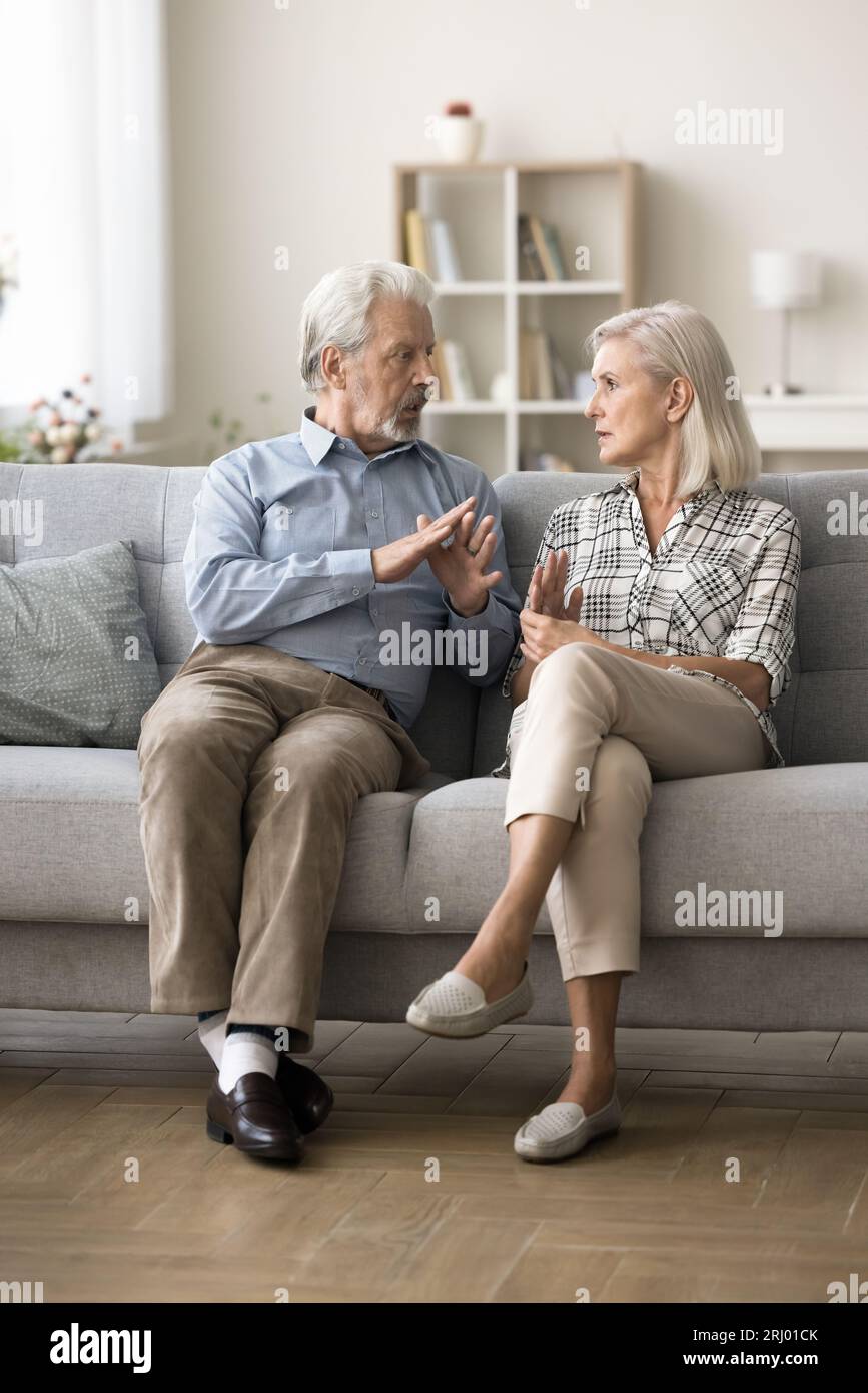 Serious elder grey haired husband and wife talking on couch Stock Photo ...