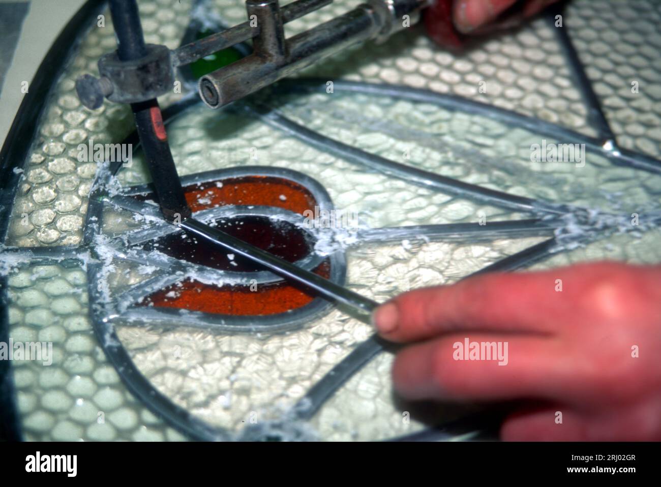 Warming solder in a stained glass window. solder has a low melting ...