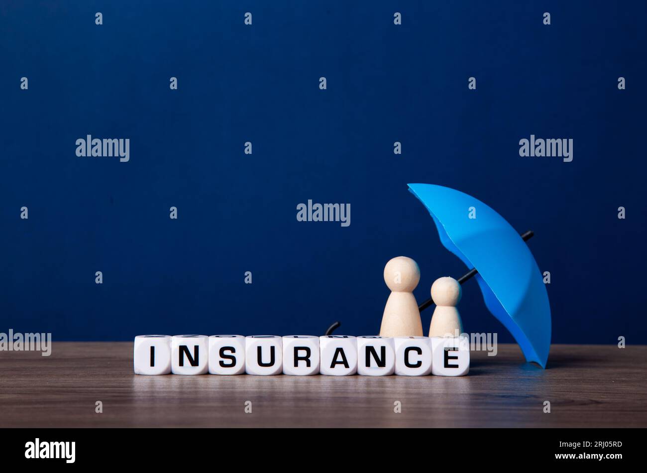 Blue toy umbrella and wooden doll figures. Insurance coverage concept ...
