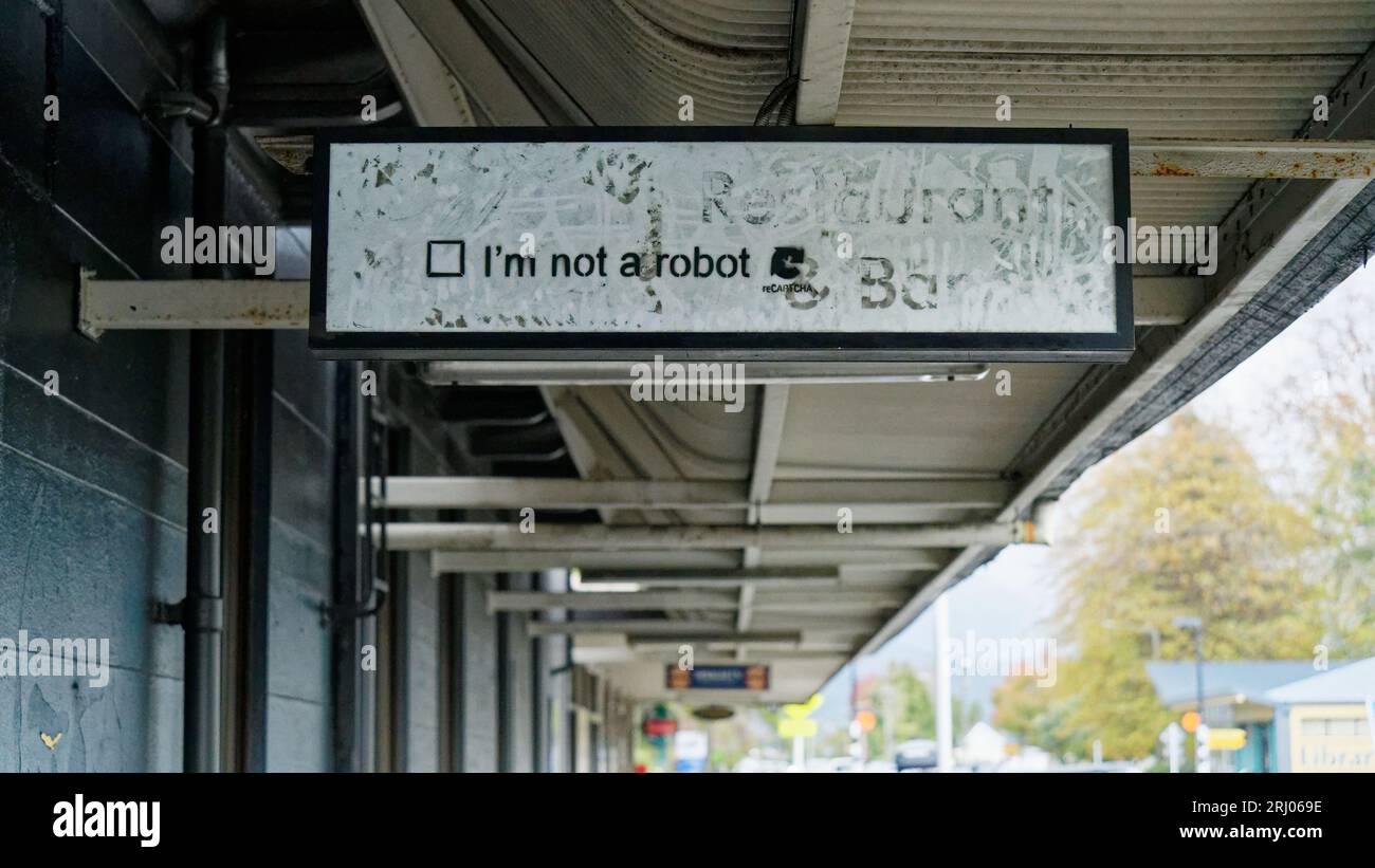 A mysterious I'm not a robot sign hanging over a pavement beside a ...
