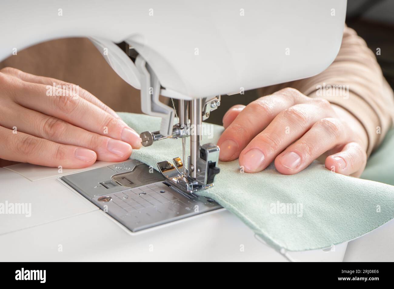 Female hands stitching green fabric on modern sewing machine at ...