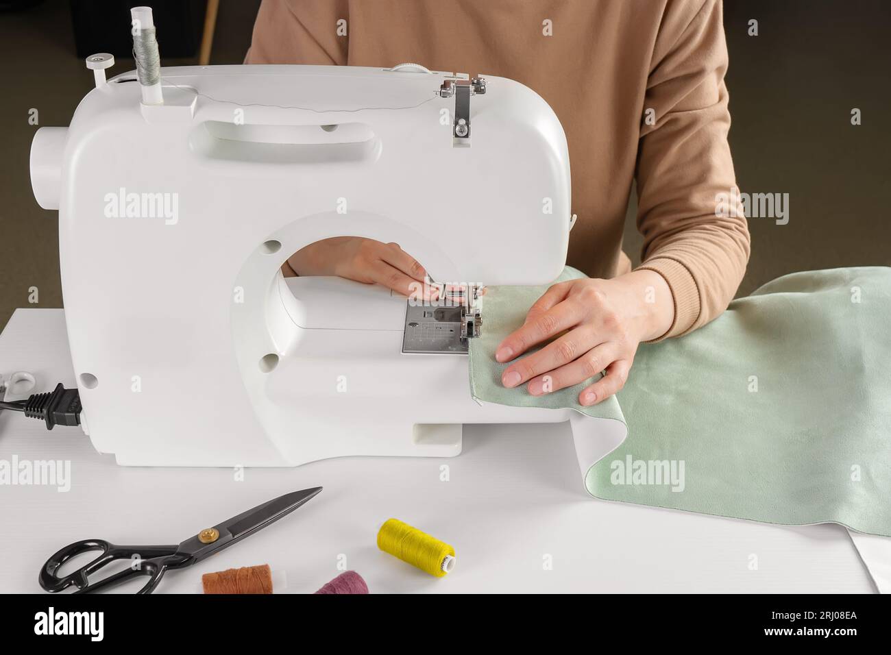 Female hands stitching green fabric on modern sewing machine at ...