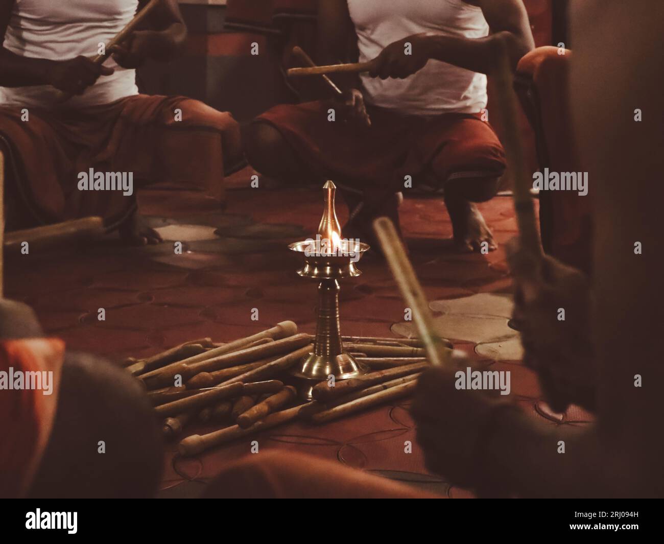 men performing a stick dance ritual around a traditional oil lamp with ...