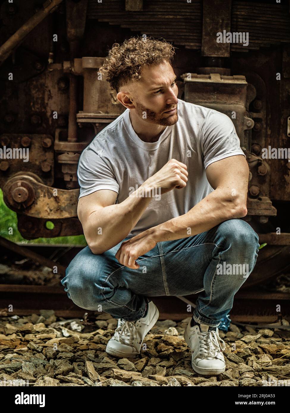 Photo of a man sitting on a train track next to a train Stock Photo - Alamy
