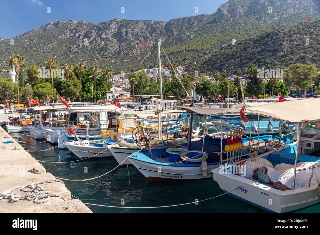 Kas harbour lined with fishing boats and mountains in the background ...