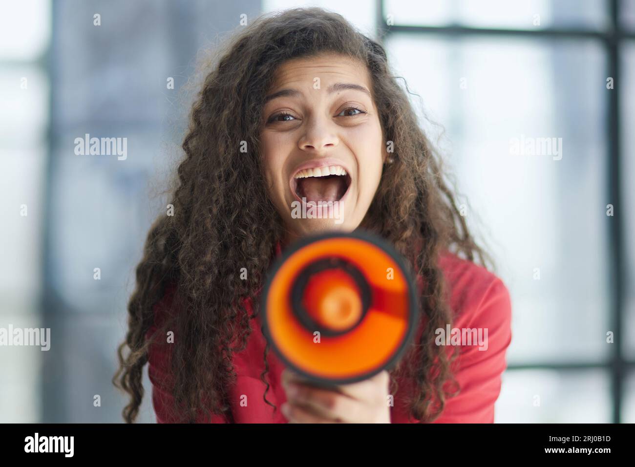 Beautiful girl shouting into a megaphone in a modern office Stock Photo ...