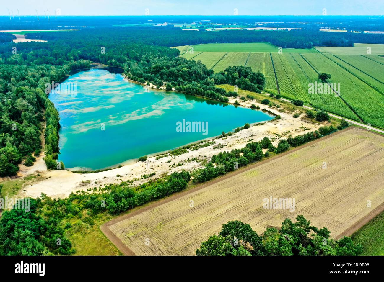 Aerial view of a blue gravel pond near Gifhorn, Germany between green ...