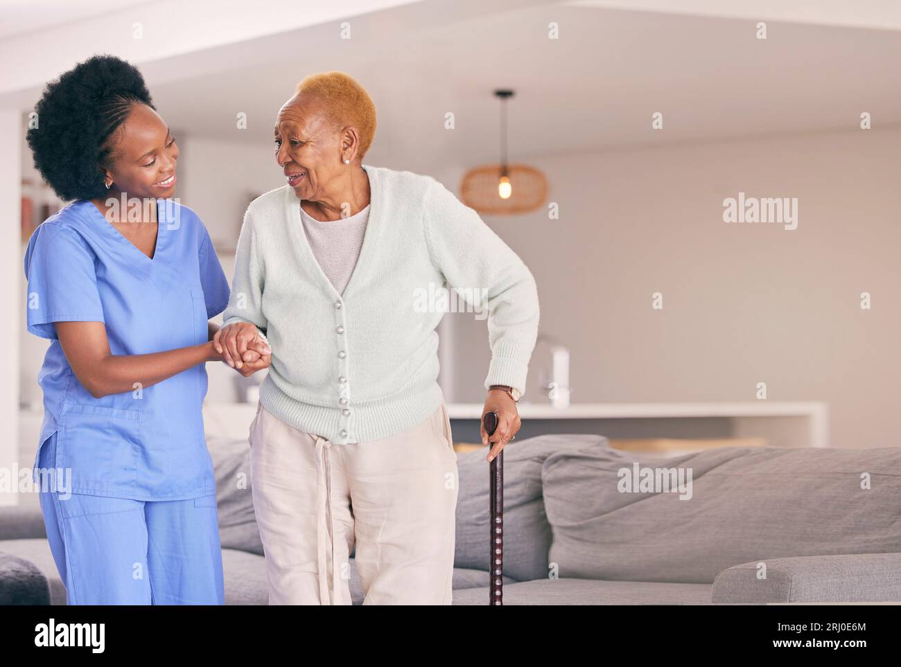 Nurse, holding hands and senior black woman with walking stick, help or smile in home. Caregiver ...