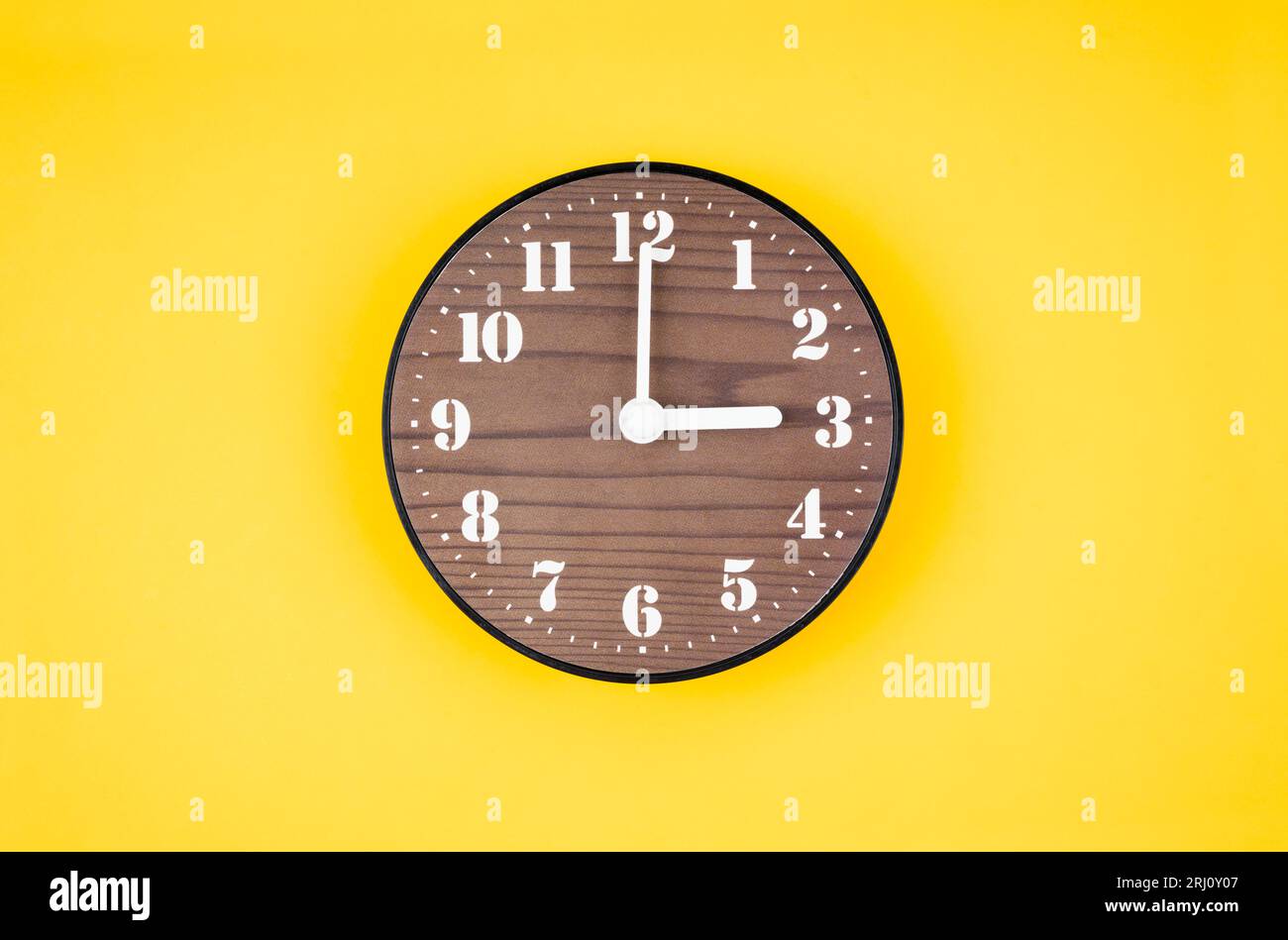 Retro wooden clock at 3 O' clock on yellow color background Stock Photo ...