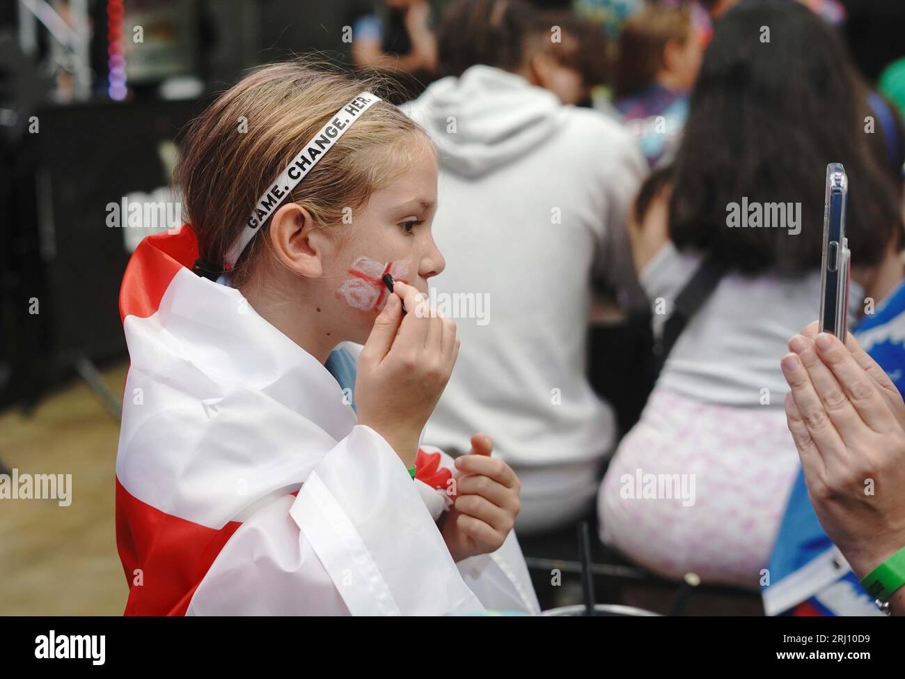 A young England fan painting a St George Cross on her face during a ...