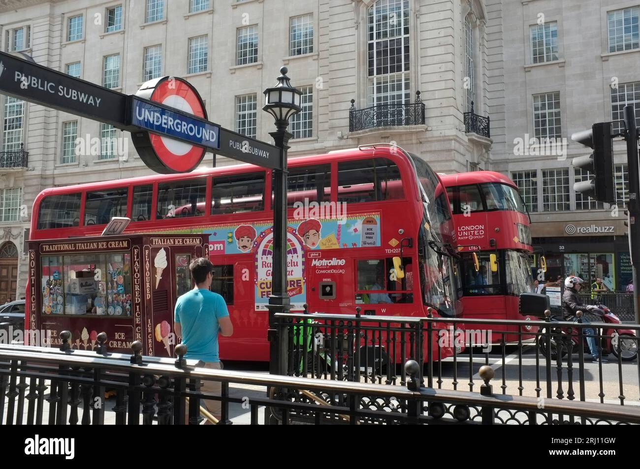 two double decker london busses next to an underground tube station ...