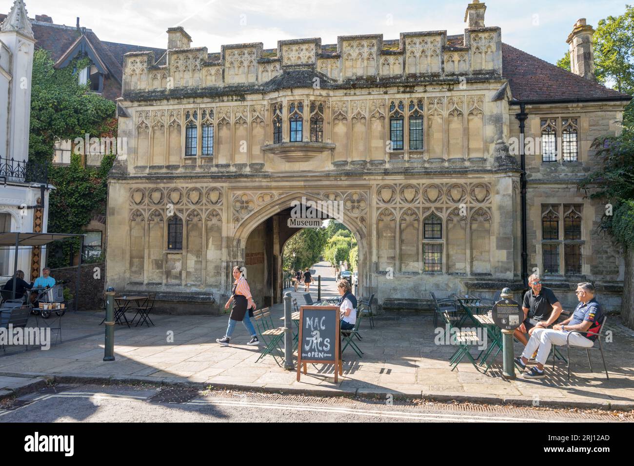 People relaxing at an outdoor cafe in front of the Great Malvern Priory ...
