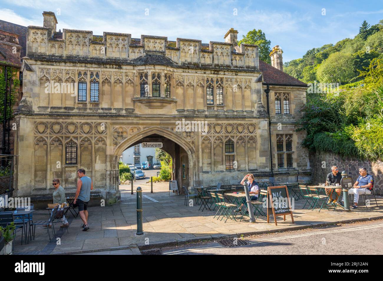 People relaxing at an outdoor cafe in front of the Great Malvern Priory ...