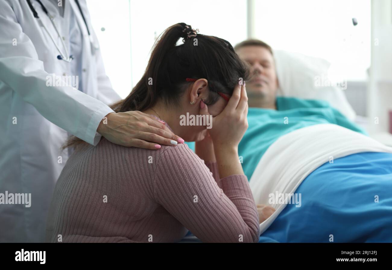 Woman in clinic crying near man in hospital bed Stock Photo - Alamy