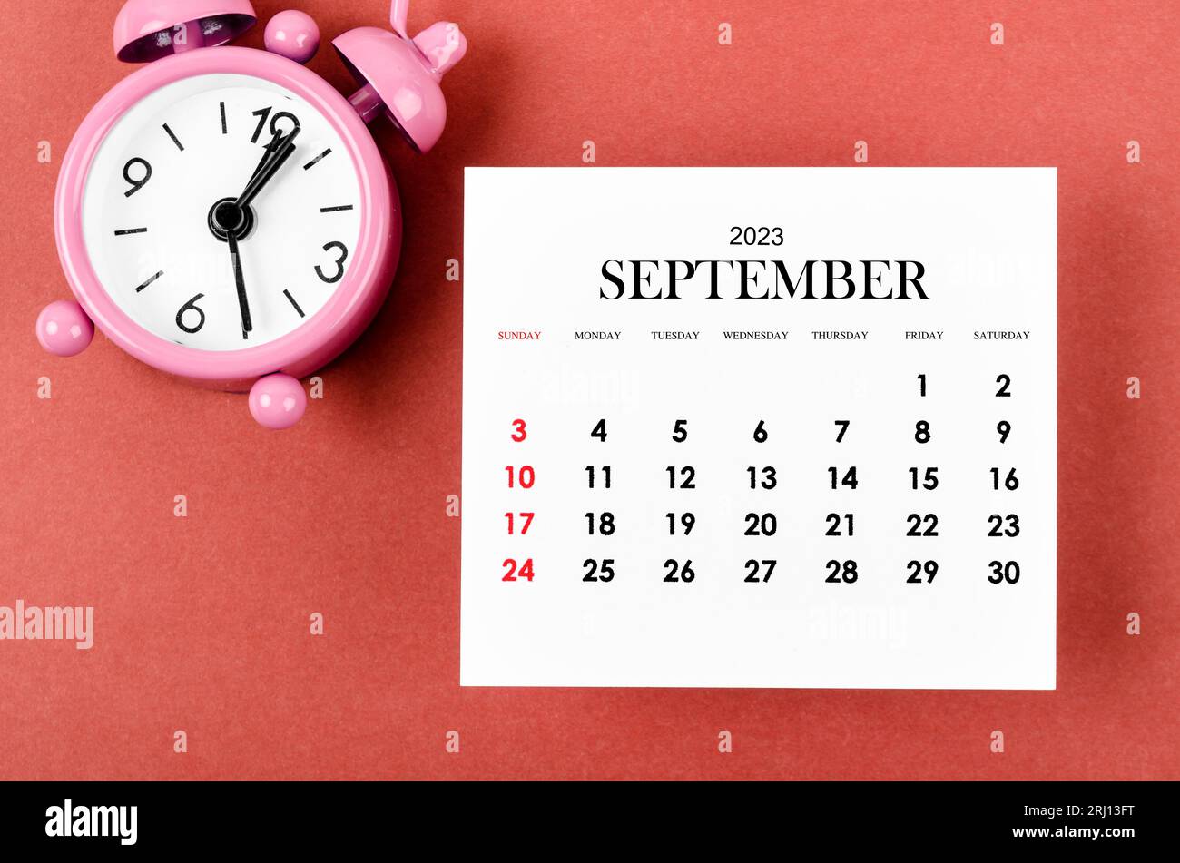 September 2023 Monthly calendar year with alarm clock on red background ...