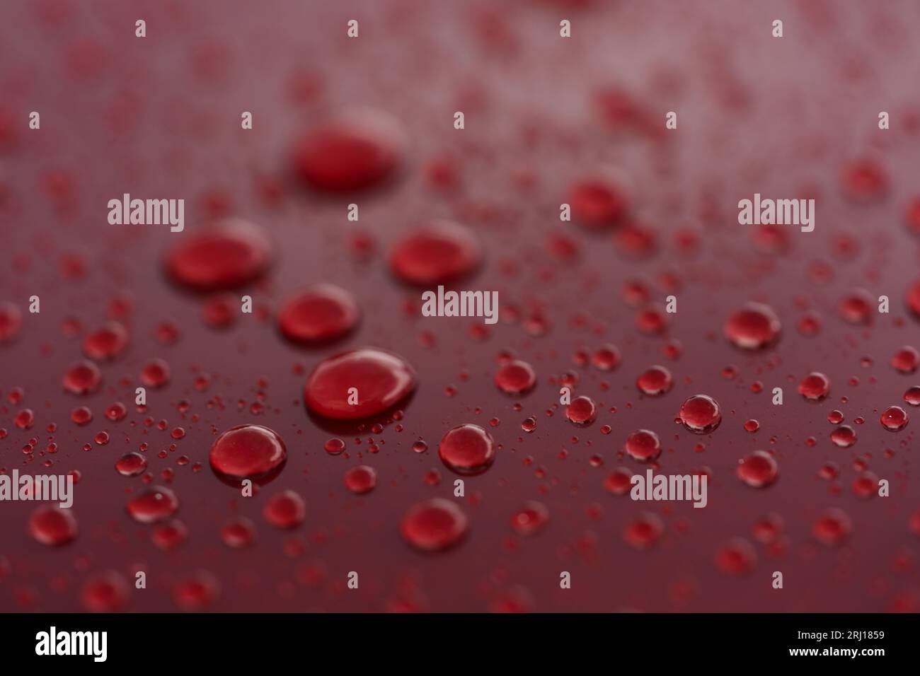 Rain droplets on red sports car surface with hydrophobic treatment ...