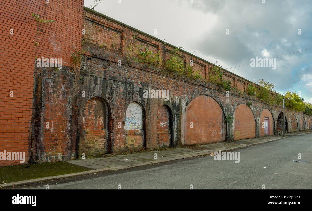 A line of bricked-up archways supporting a railway line that runs ...