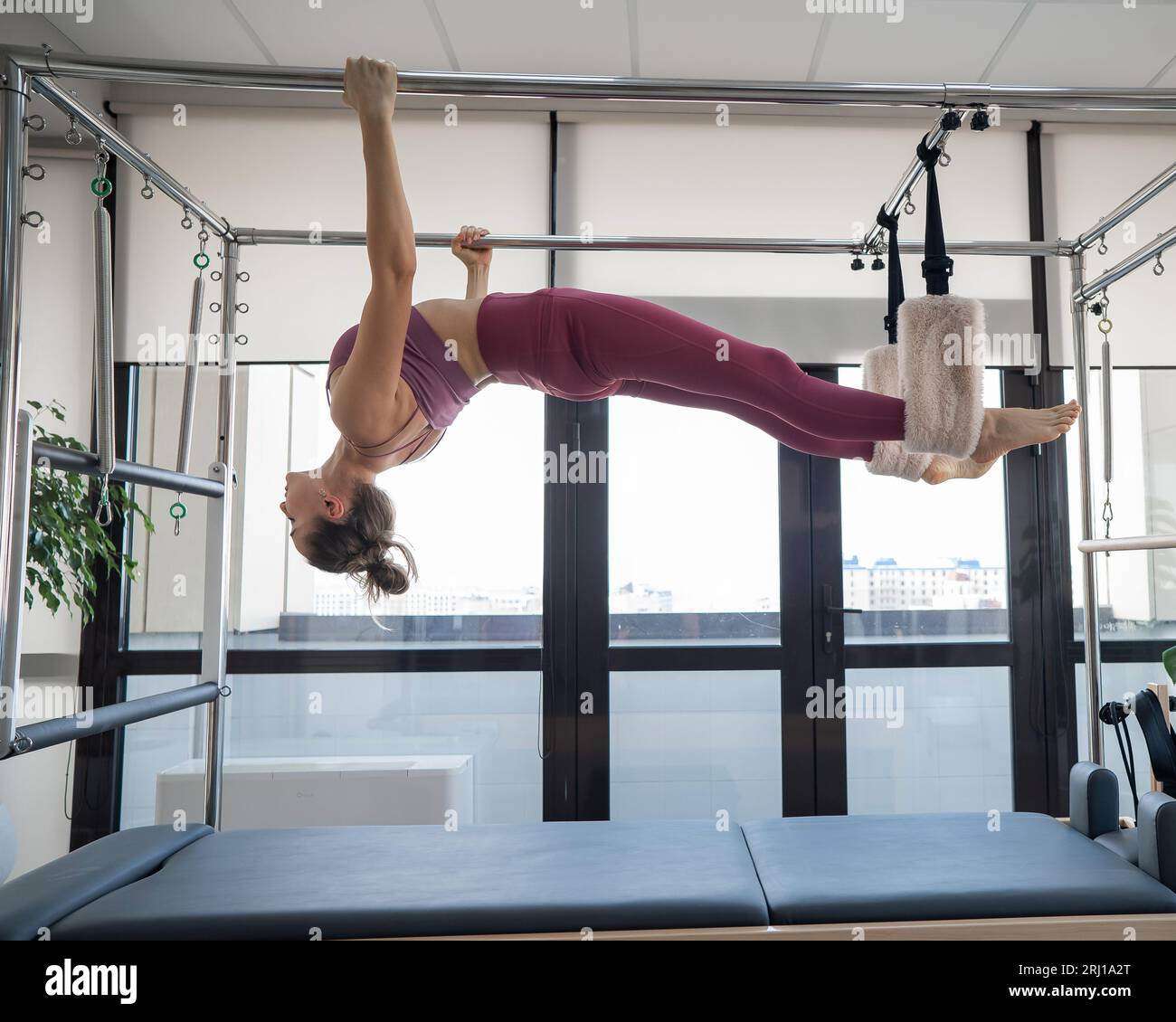 A caucasian woman is engaged in Pilates on a reformer simulator ...