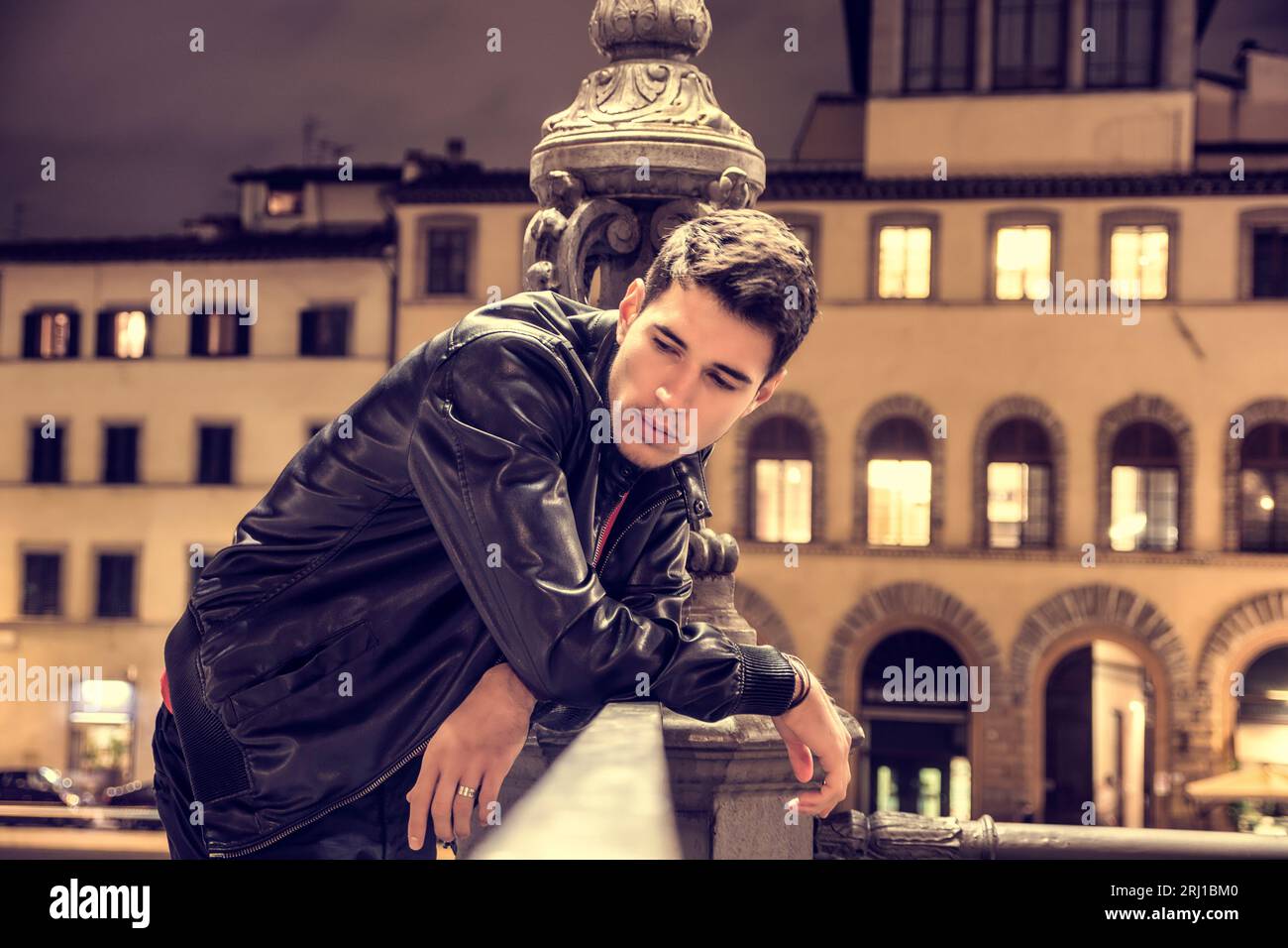 Photo of a man leaning on a railing in front of a building Stock Photo ...
