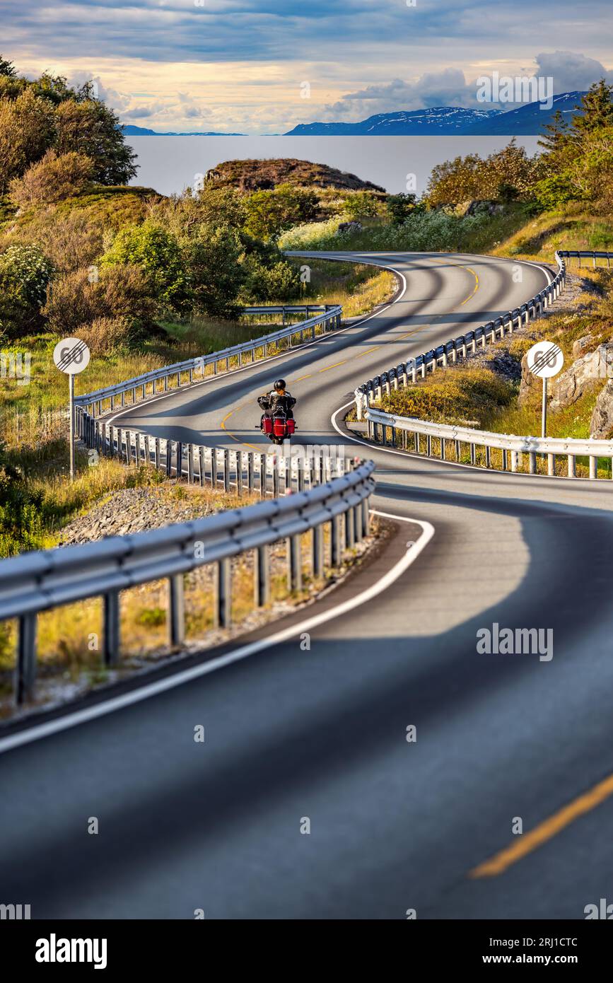 Couple rides a motorcycle on a winding Atlantic road in Norway ...